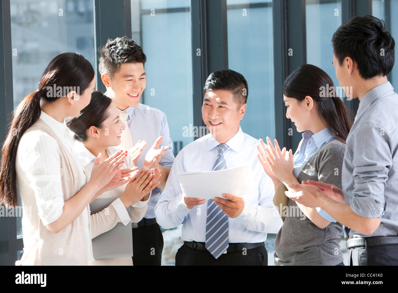 Businesspeople clapping and congratulating team leader Stock Photo - Alamy