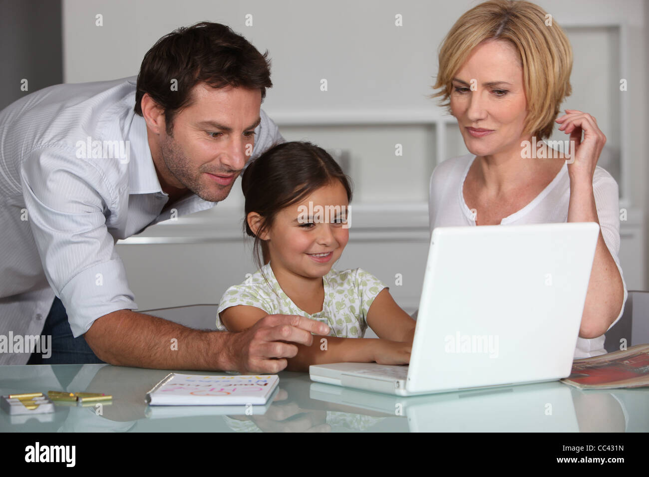 Young girl using a laptop computer with her parents Stock Photo - Alamy