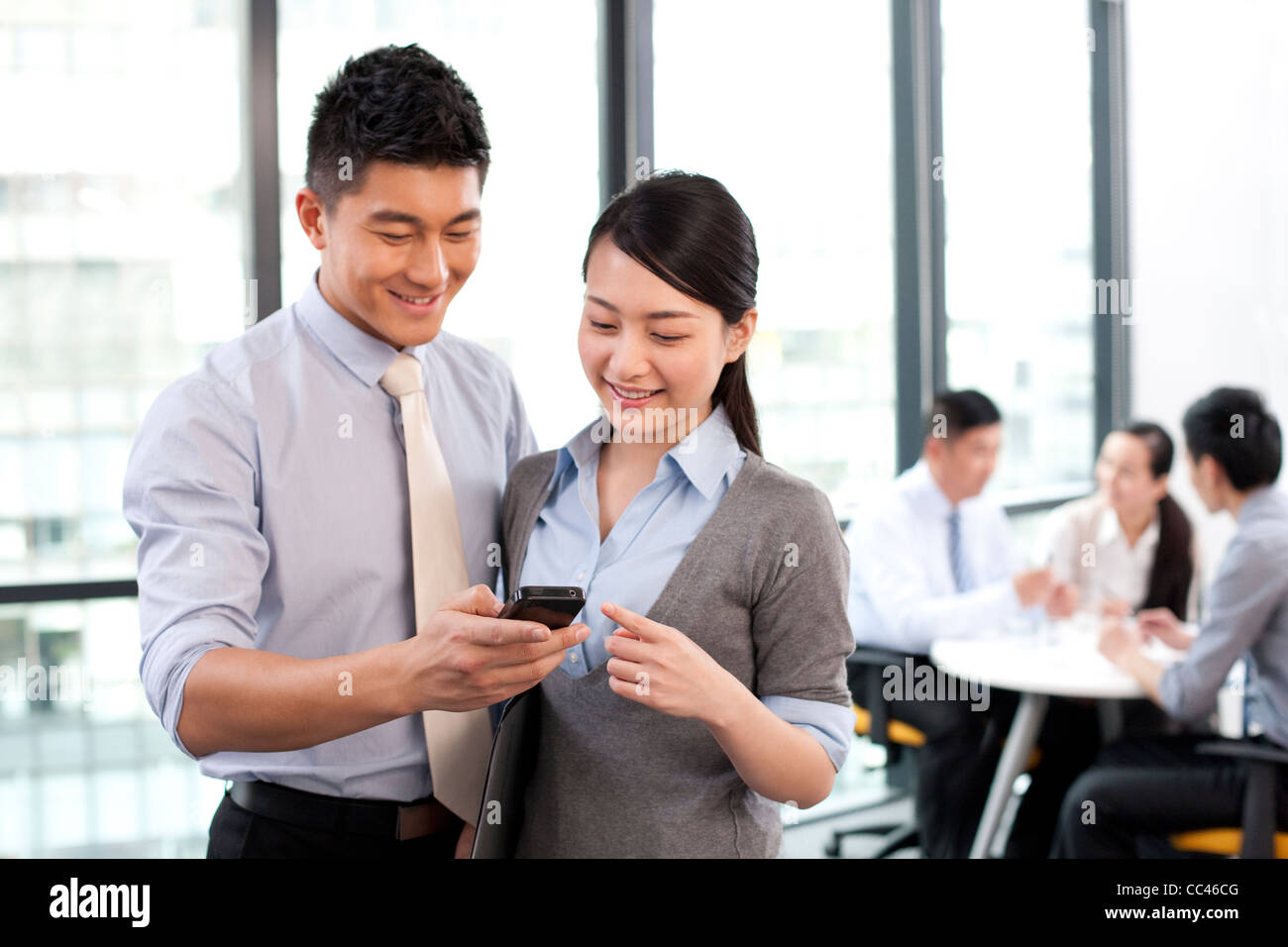 Businesspeople looking at a mobile phone screen Stock Photo - Alamy