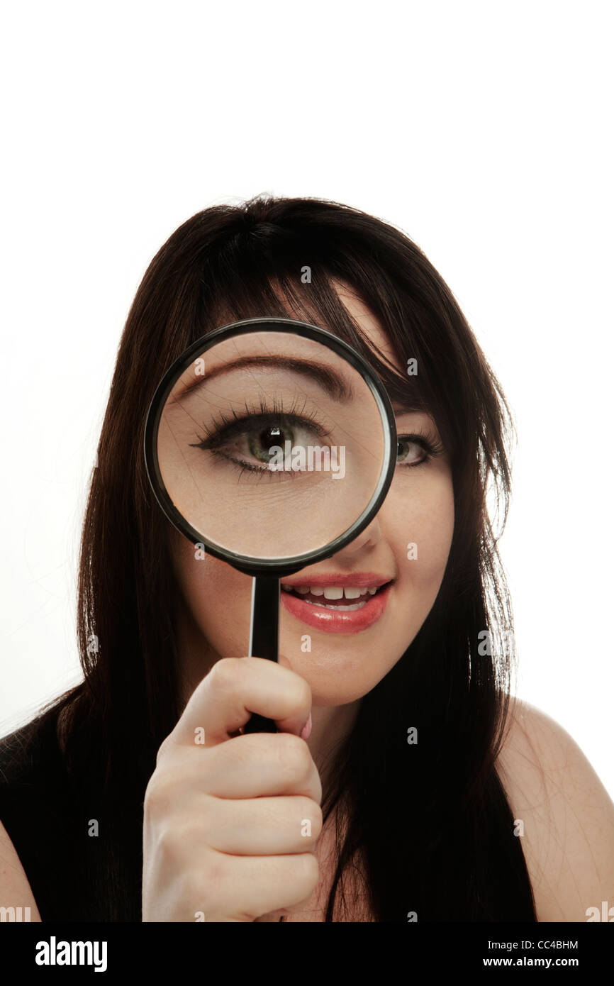 woman holding a magnifying glass up to her eye so it looks really big Stock Photo - Alamy