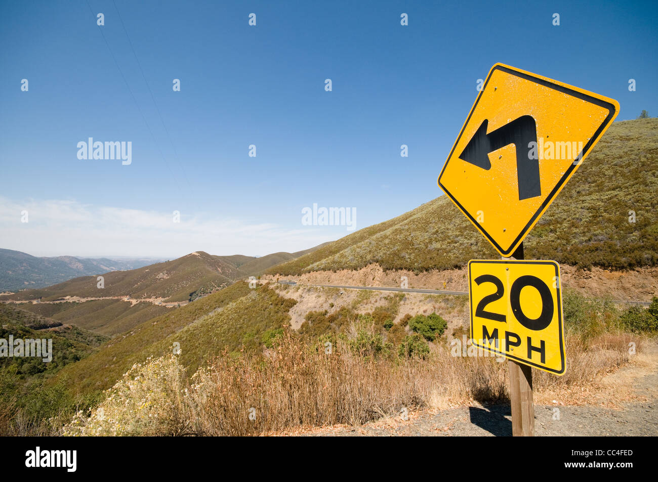 Yellow road warning sign left turn 20mph with long winding road ...