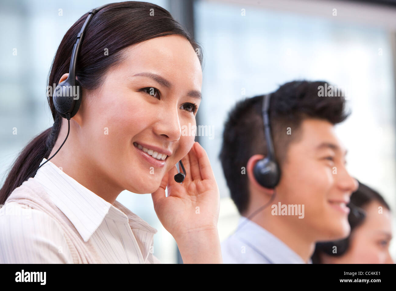 Smiling call center agent with her colleagues in the background Stock ...