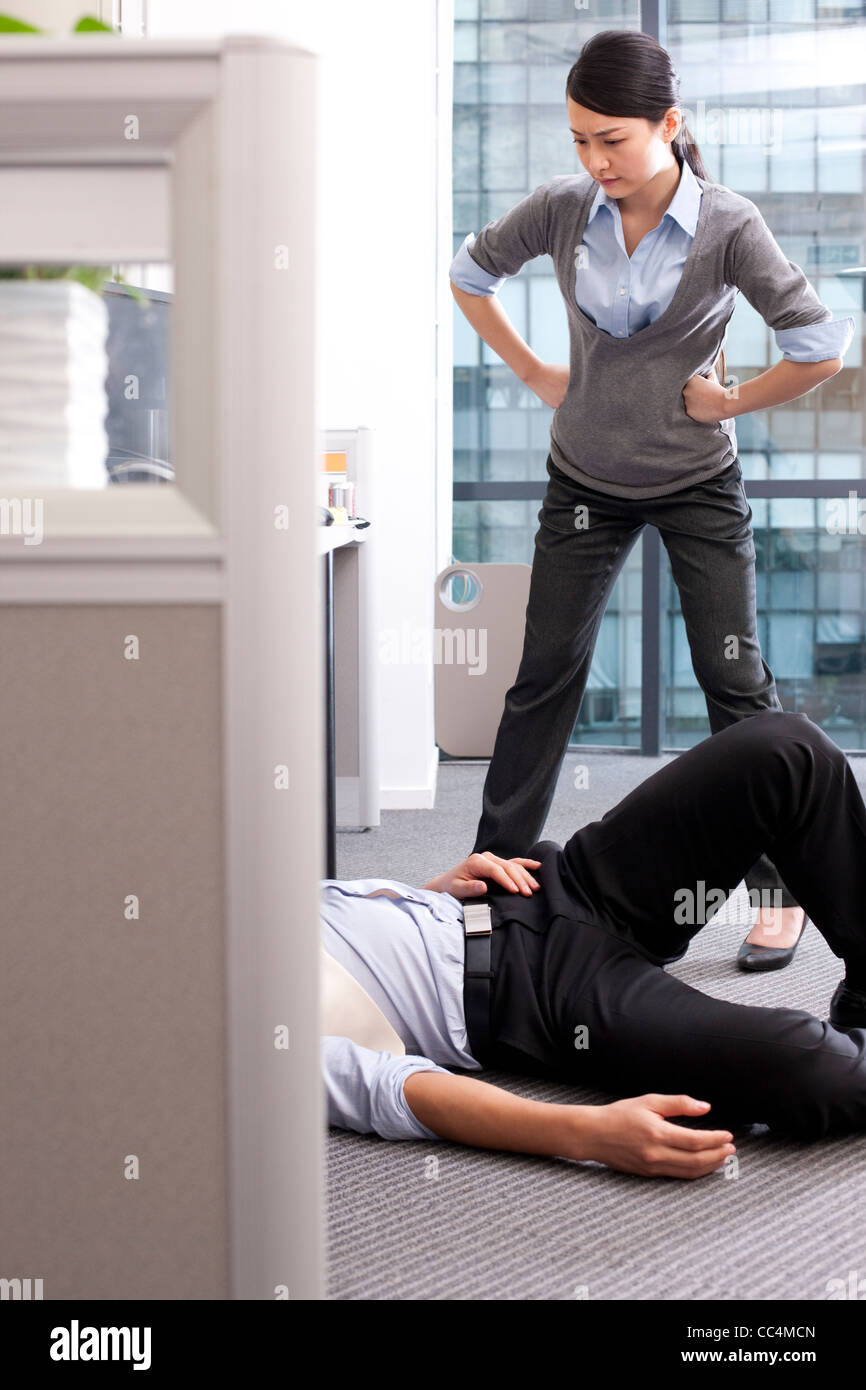 Businesswoman angry at her colleague lying on the floor Stock Photo - Alamy