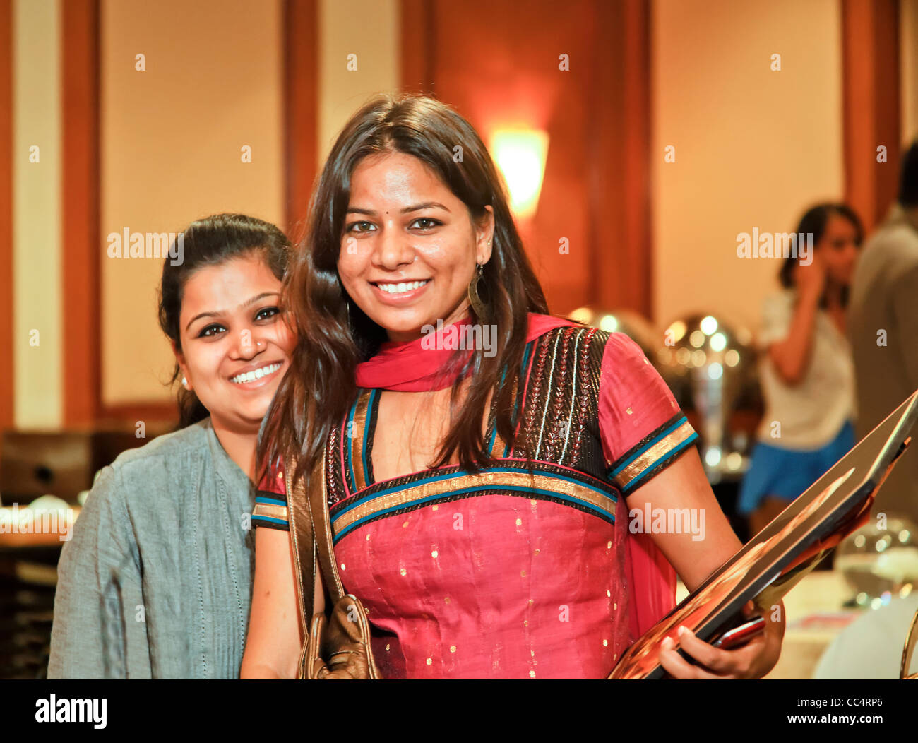 Two smiling Indian pretty hostesses at an event with clip board and ...