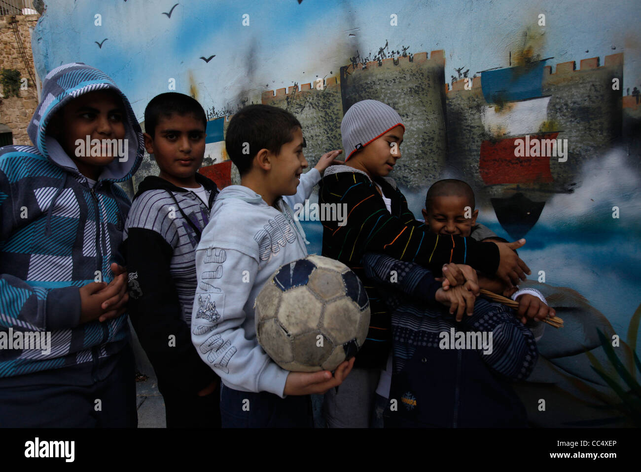 Young Israeli Arab kids playing in front of a painted wall depicting ...
