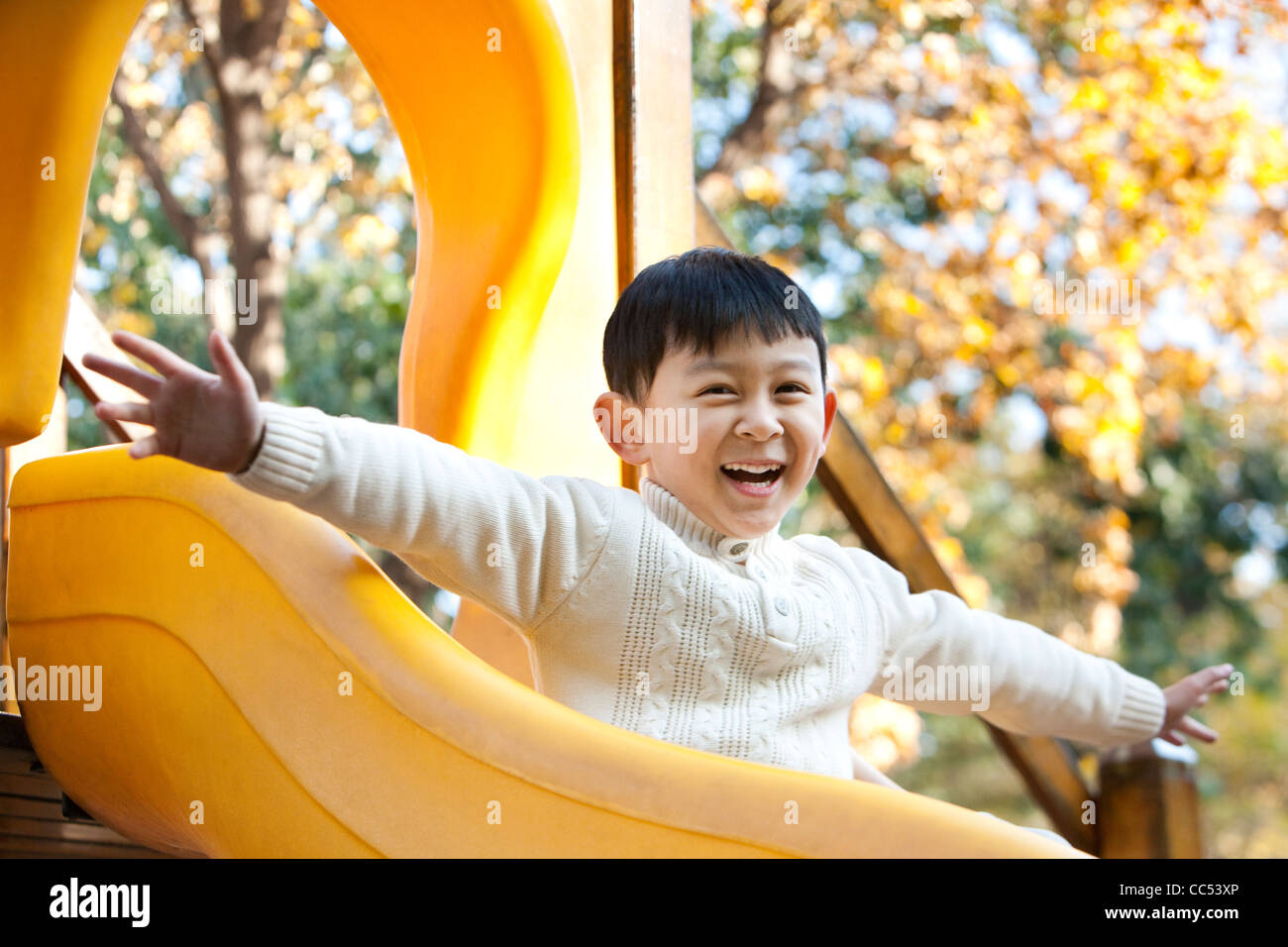 Boy playing on playground slide Stock Photo - Alamy