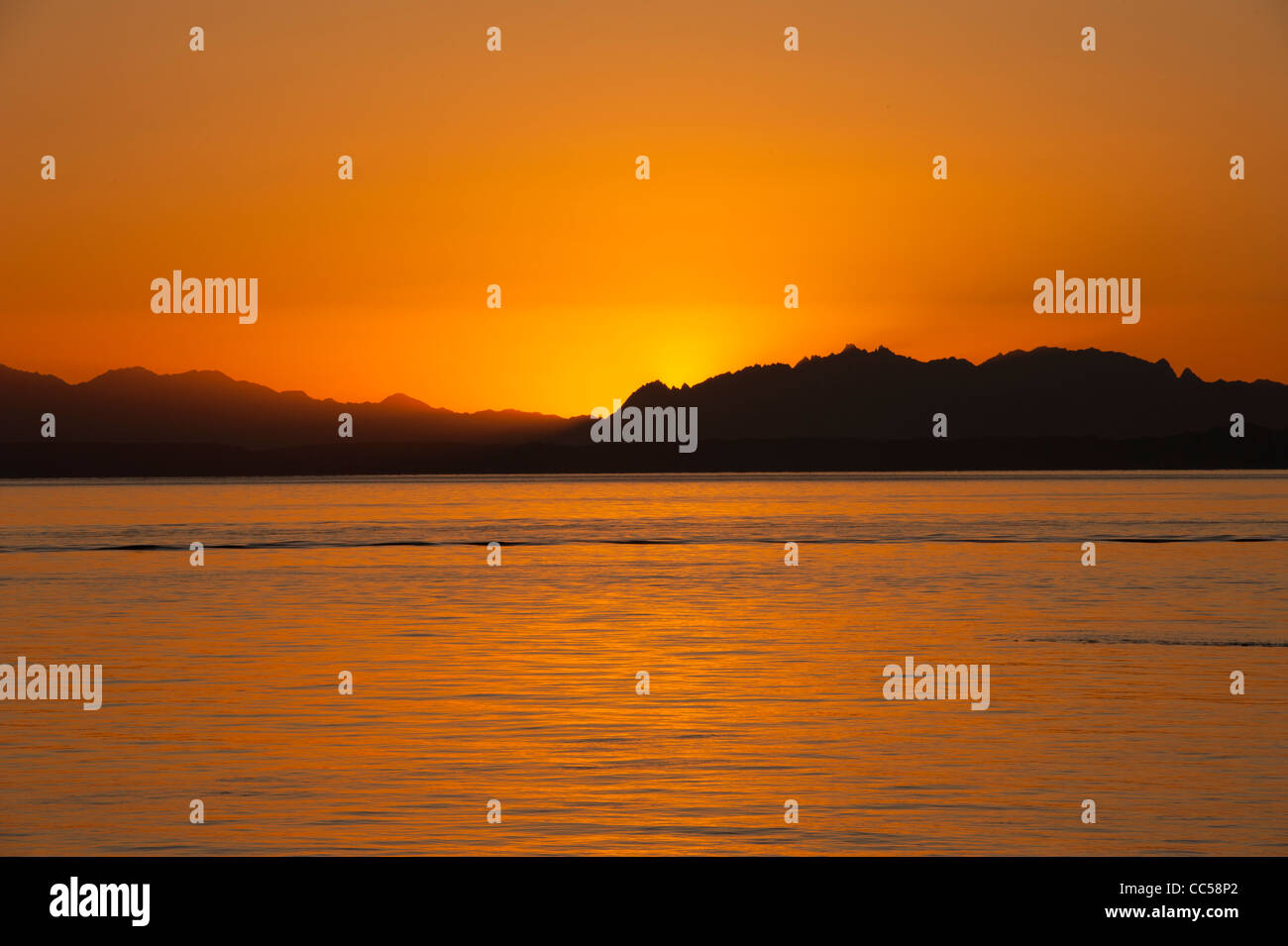 Beautiful orange sunset over mountains on a ocean coastline Stock Photo ...
