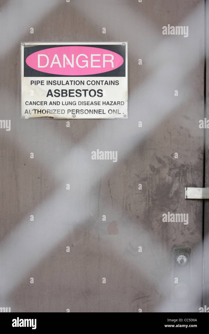Asbestos warning sign posted on door to abandoned factory building ...