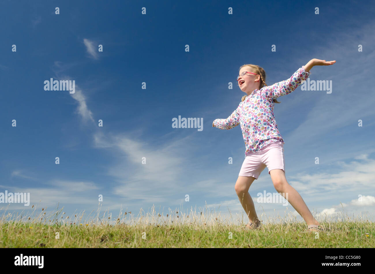 Happy little girl jumping in front of blue sky Stock Photo - Alamy