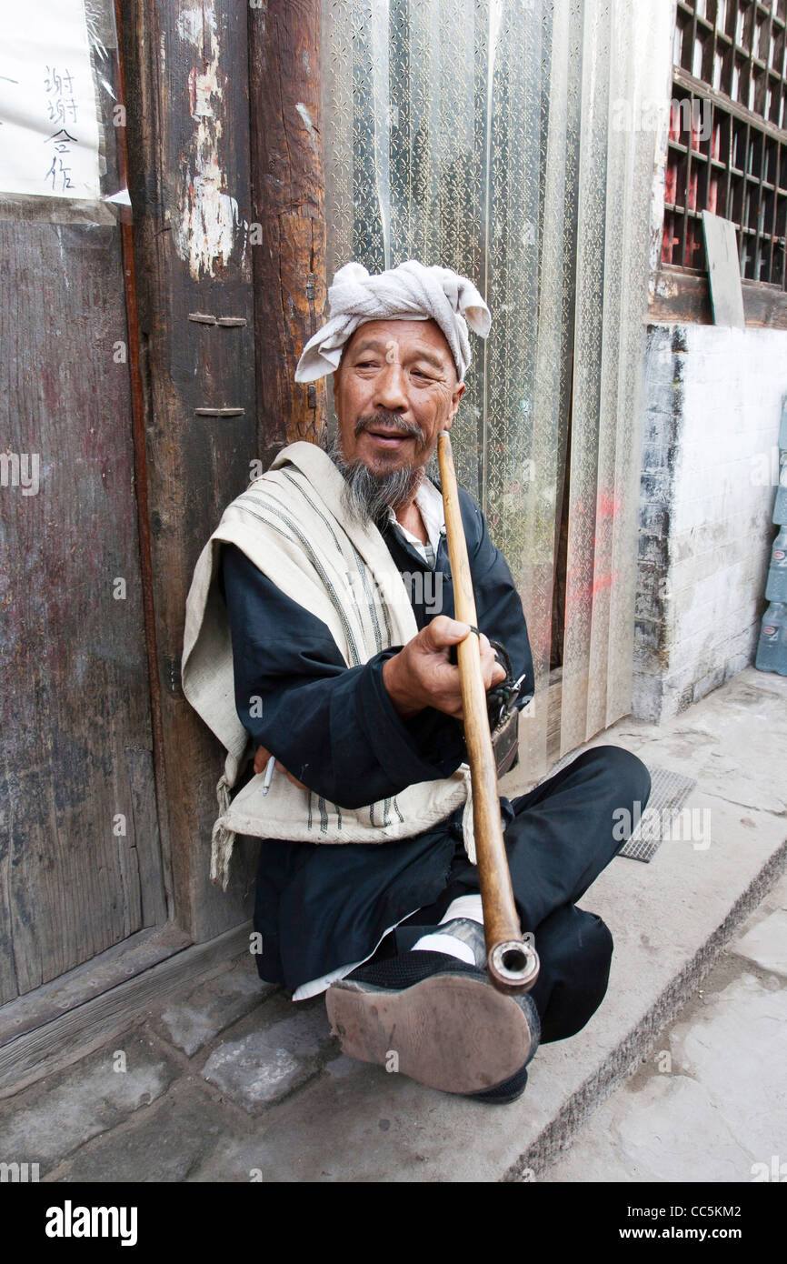 Elderly man smoking by a long tobacco pipe, Qikou Old Town, Lvliang ...