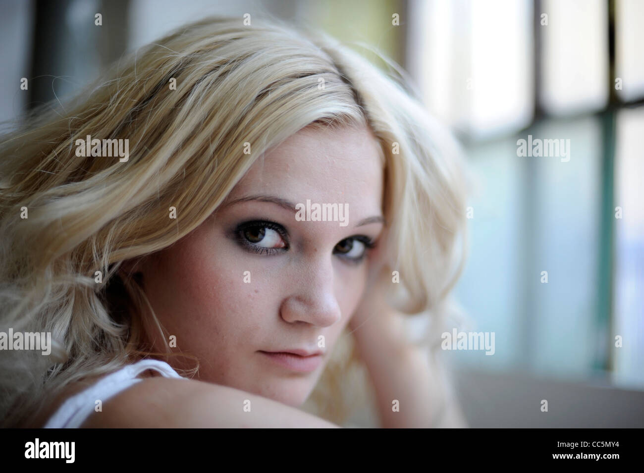 Fashion headshot of young blonde with make up shot in warehouse ...