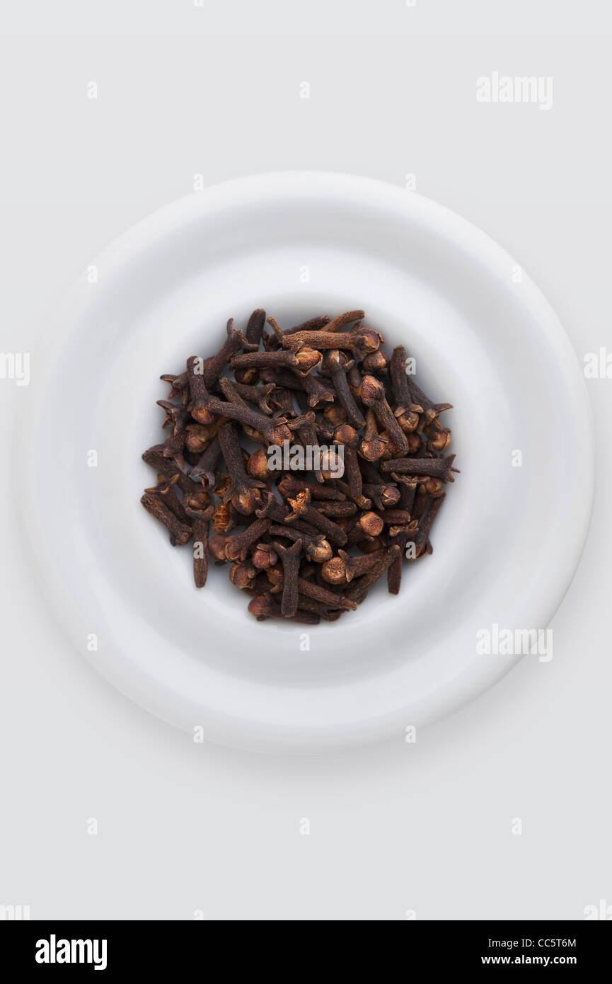 Cloves on a white china plate against a white background Stock Photo ...
