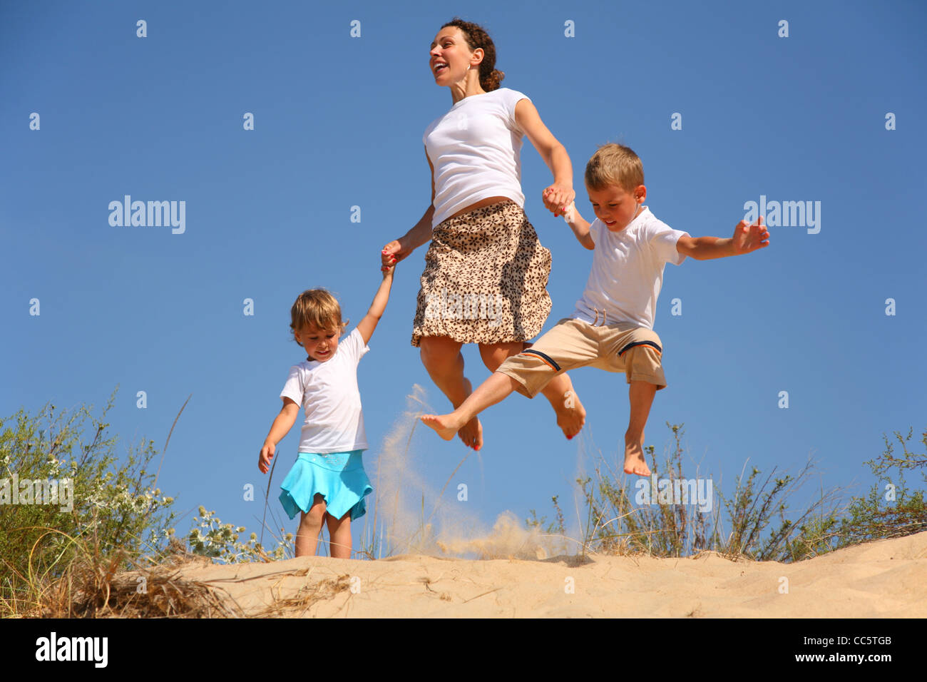 Mother with children jumping on sand Stock Photo - Alamy