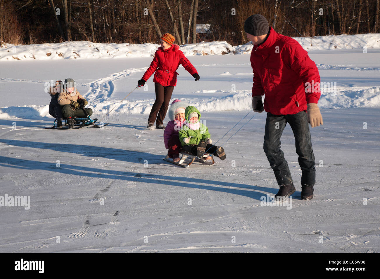 Parents pull four children on sleds Stock Photo - Alamy