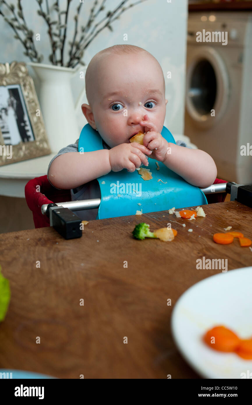 Baby boy feeding himself Stock Photo - Alamy