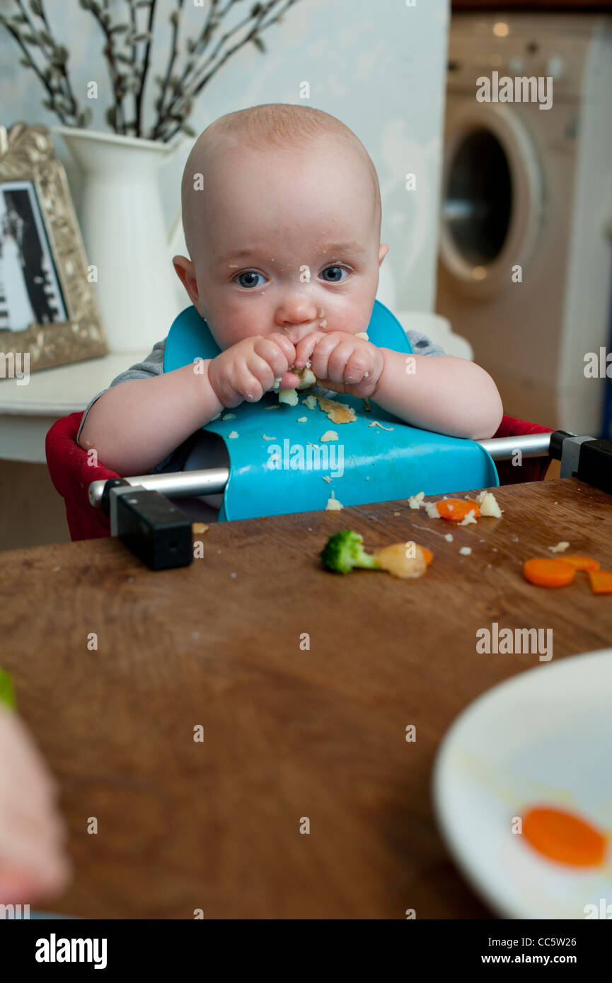 Baby boy feeding himself Stock Photo - Alamy