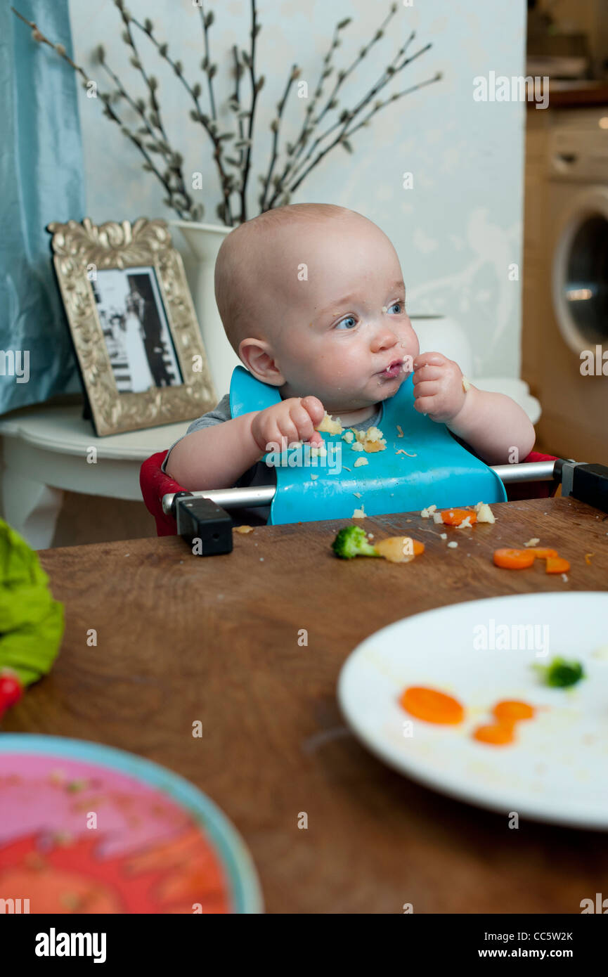 Baby boy feeding himself Stock Photo - Alamy