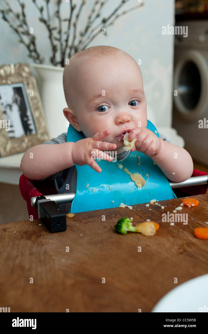 Baby boy feeding himself Stock Photo - Alamy