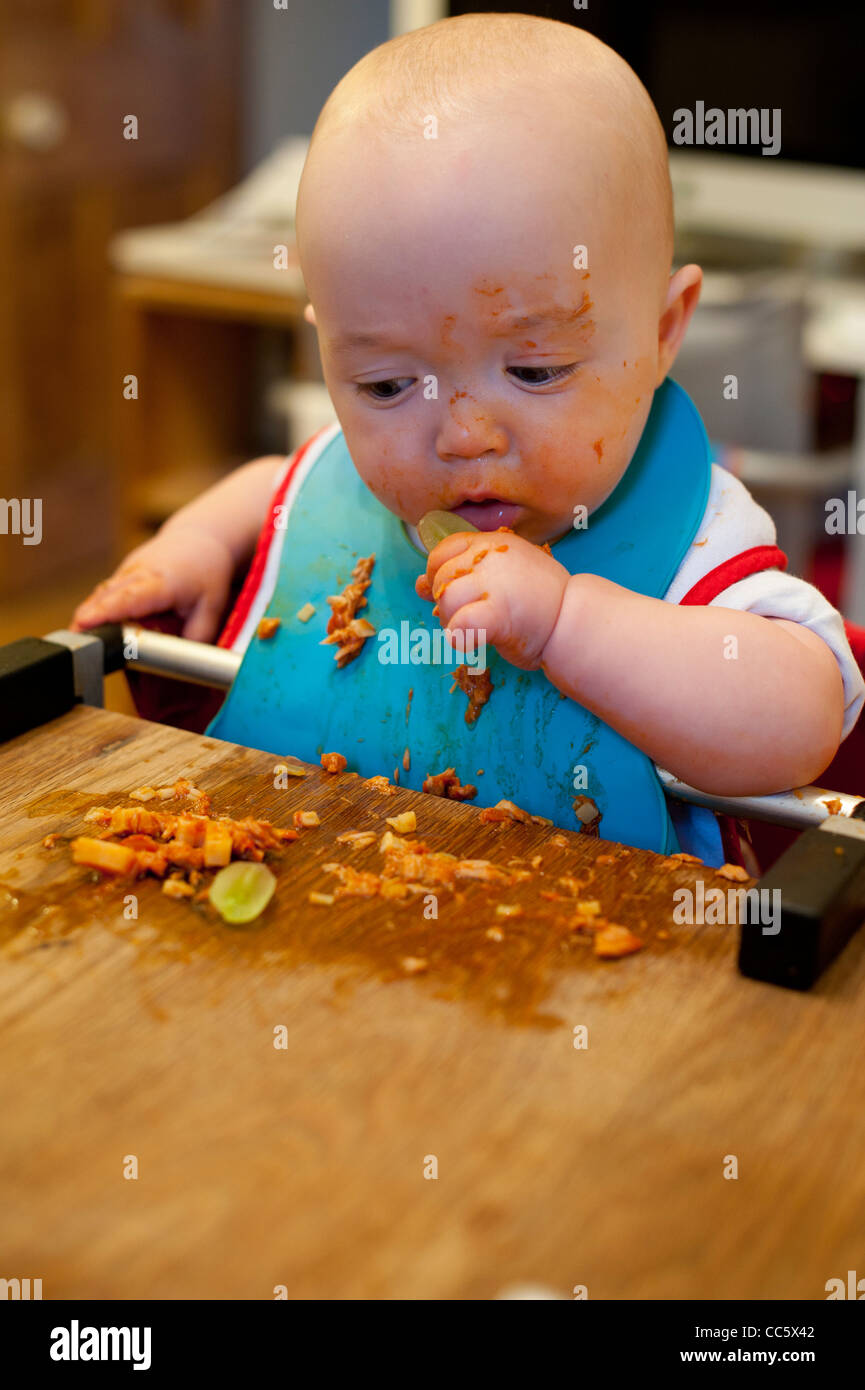 Baby boy feeding himself Stock Photo - Alamy