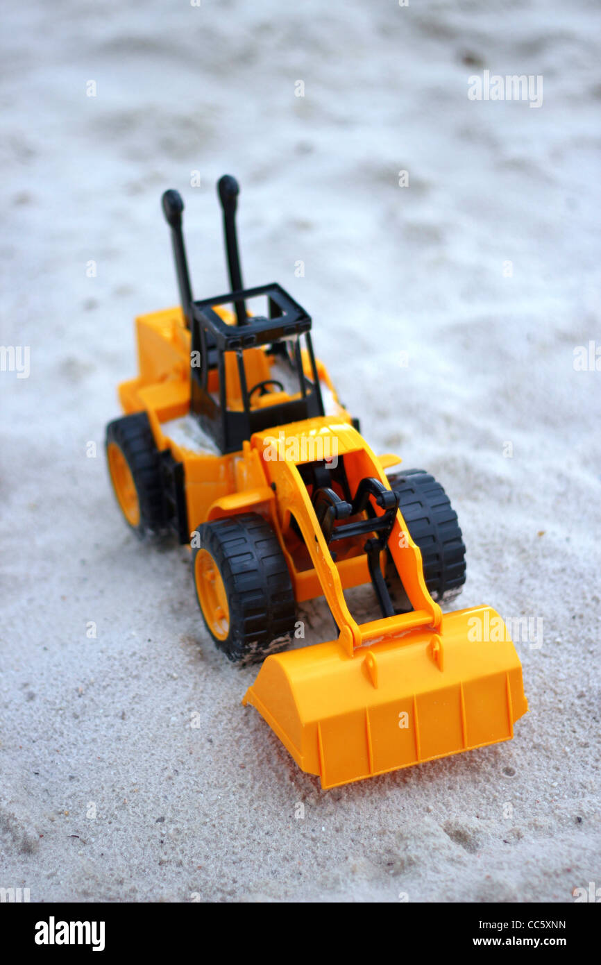 Toy bulldozer, with white sand background Stock Photo - Alamy