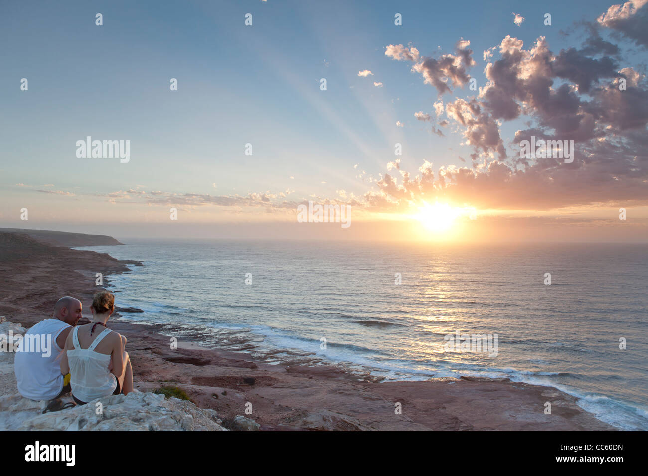 A couple enjoy a stunning sunset from the cliffs of Red Bluff Beach in ...