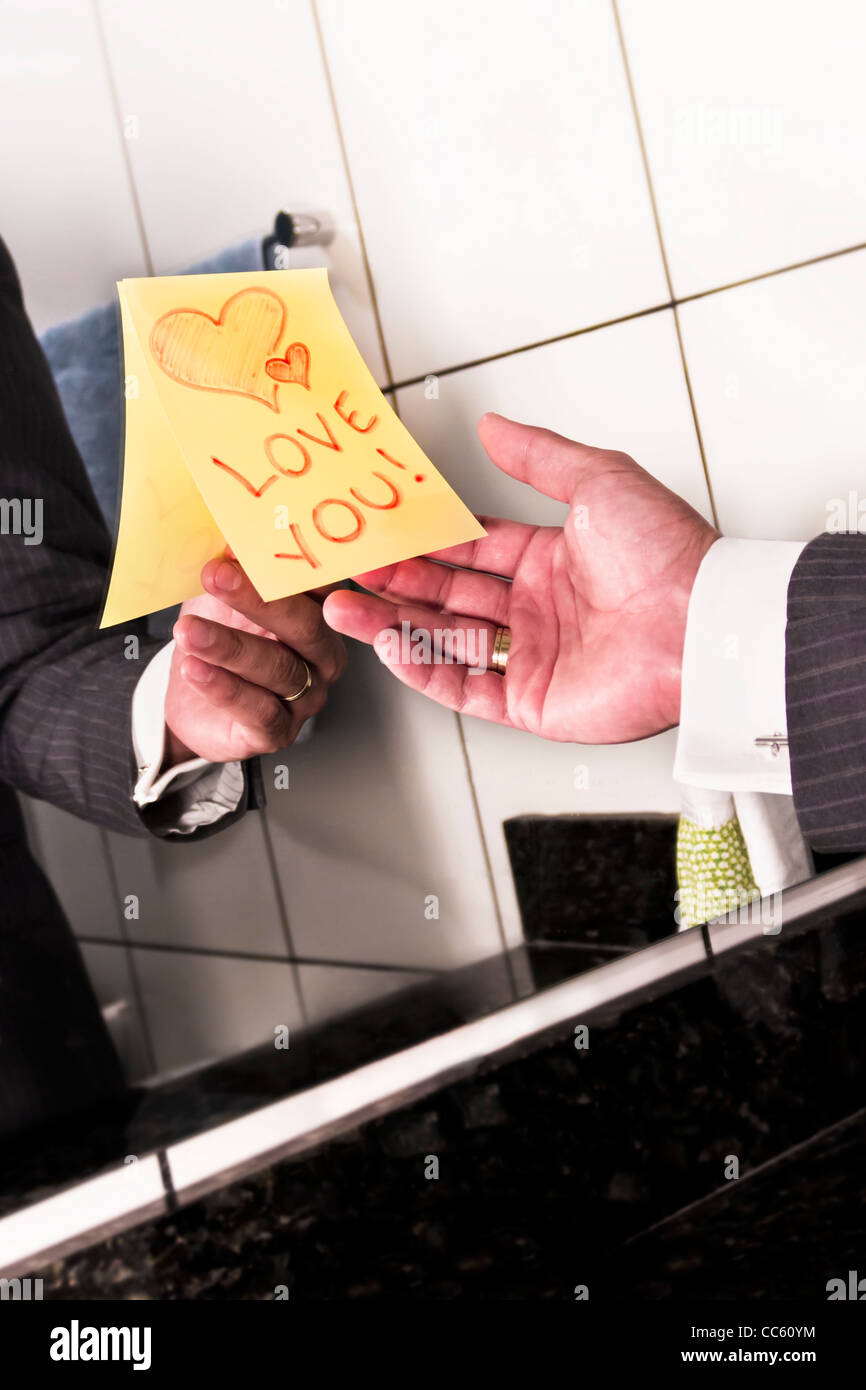 Man in suit reading a love note stuck to the mirror Stock Photo - Alamy