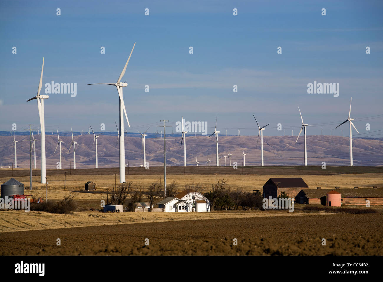 A small farm surrounded by wind turbines at wind farms along the ...