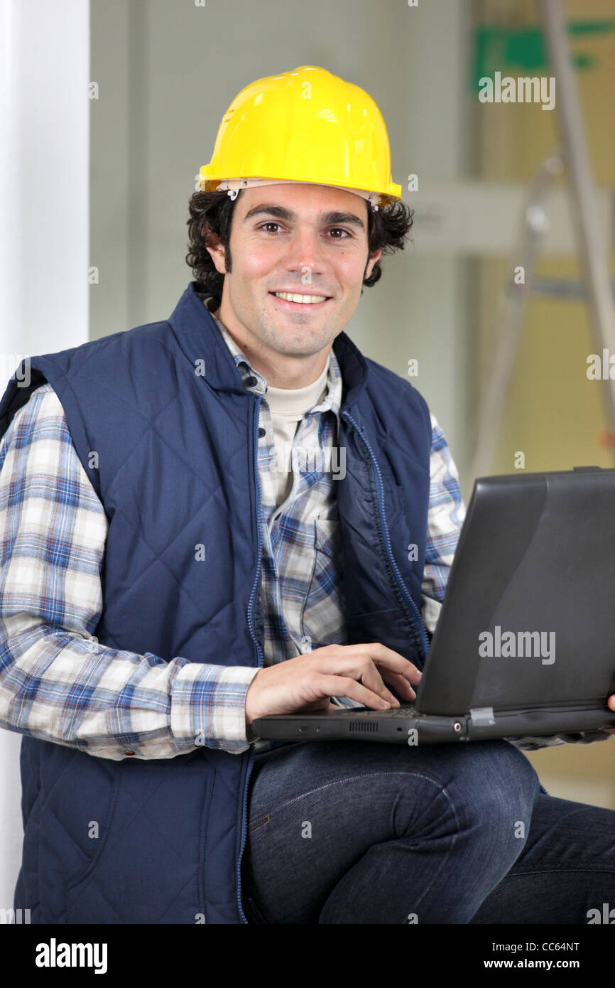 Builder sat with laptop Stock Photo - Alamy