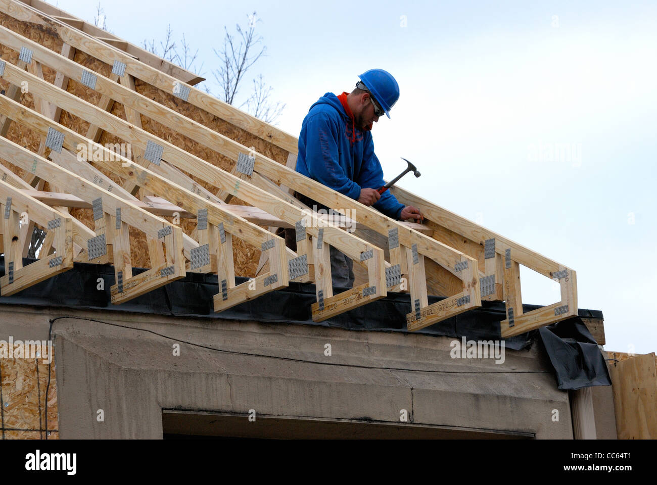 A carpenter with hammer and nail among wood frame rafters Stock Photo ...