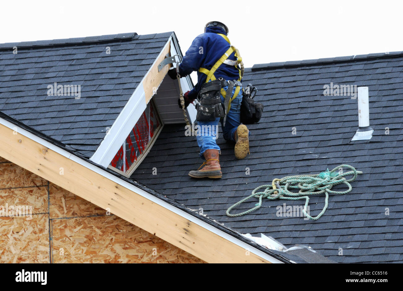Man on roof working on apartment rehab Stock Photo - Alamy