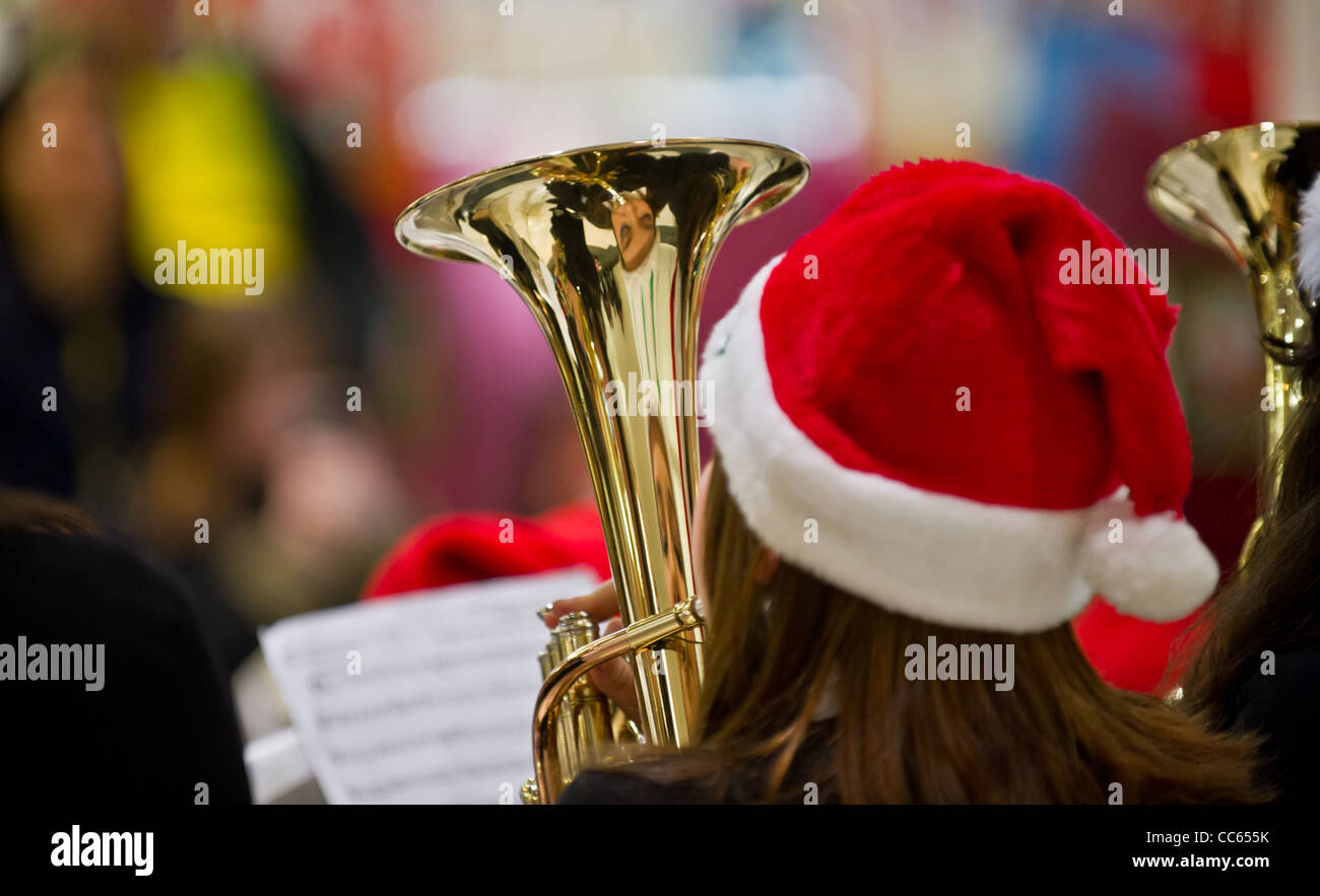 A young musician wearing a santa hat plays a brass musical instrument ...