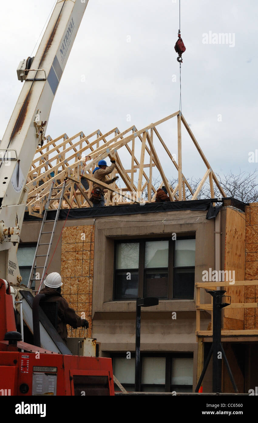 Crane operator lifts prefabricated rafter onto wood frame roof Stock ...