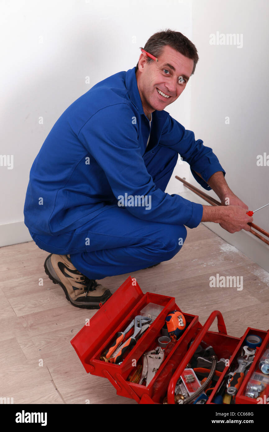 Plumber kneeling by tool box Stock Photo - Alamy