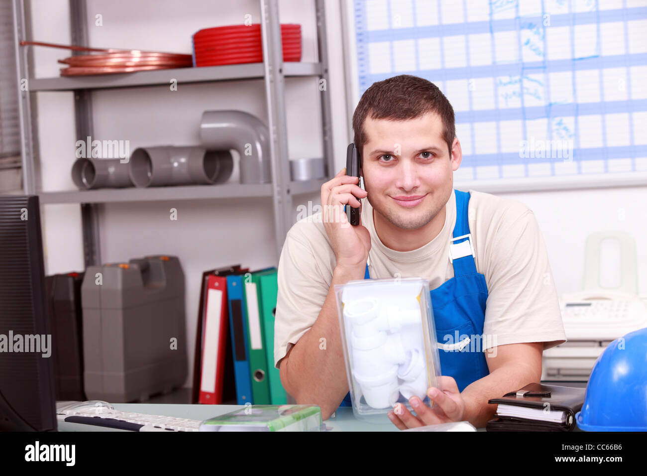 Man on telephone checking a plumbing part Stock Photo - Alamy