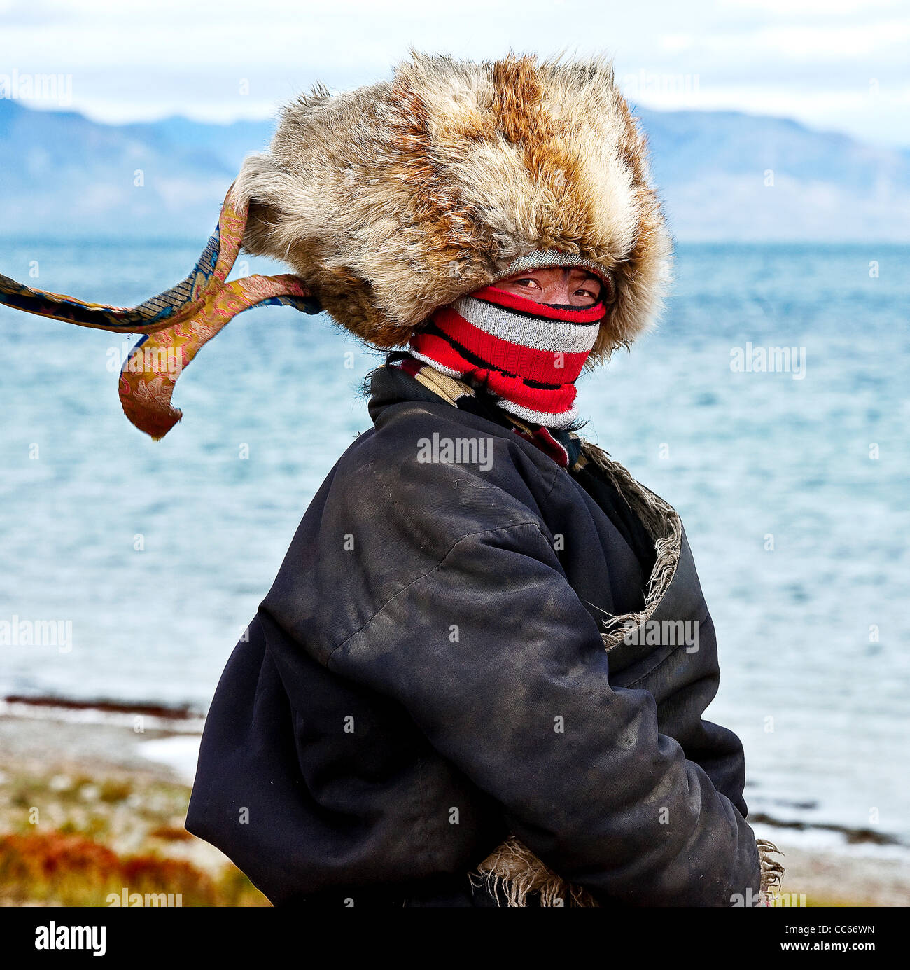 Tibetan man in traditional costume beside Lake Tangra Yumco, Ngari ...