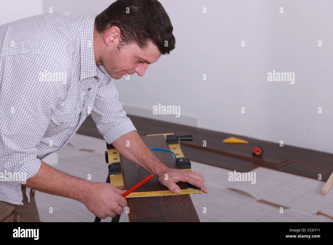 Man laying a floor and measuring a piece of wood Stock Photo - Alamy