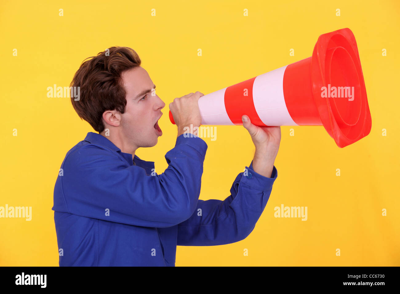 young blue collar shouting in construction cone Stock Photo - Alamy
