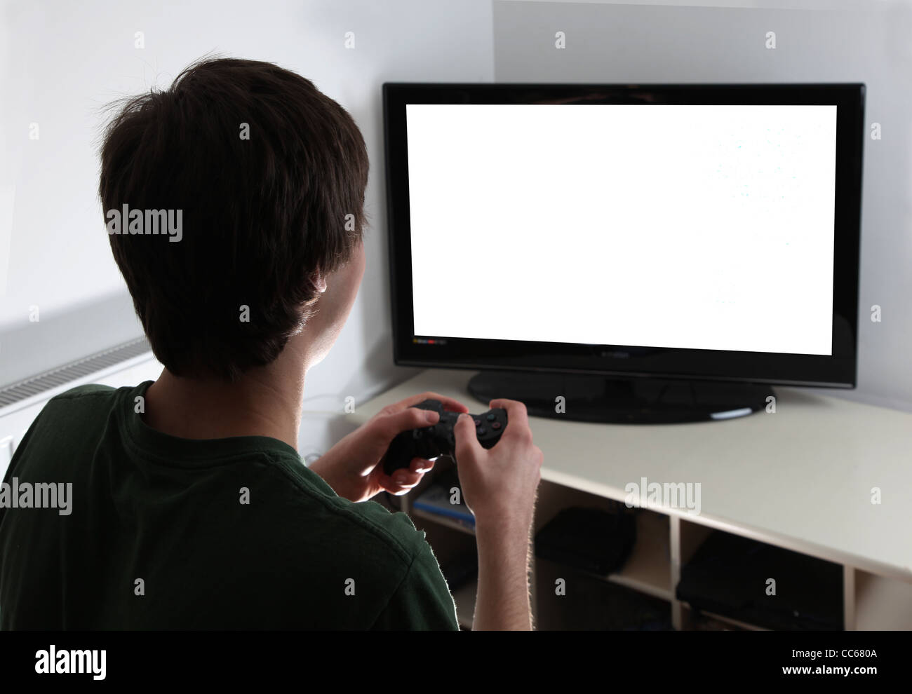 Young male sitting in front of large tv with a game controller in his ...