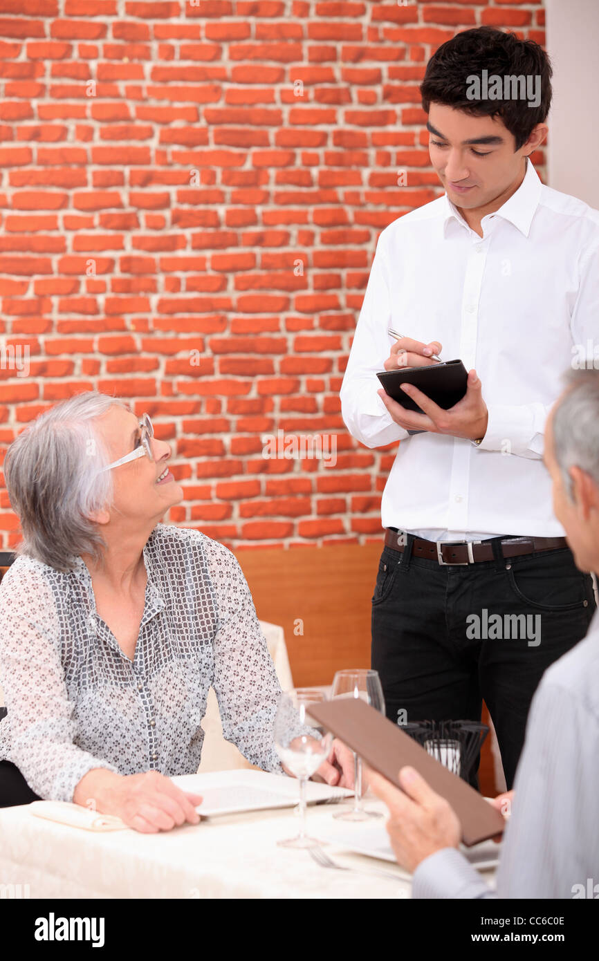 Young waiter taking an order in a restaurant Stock Photo - Alamy