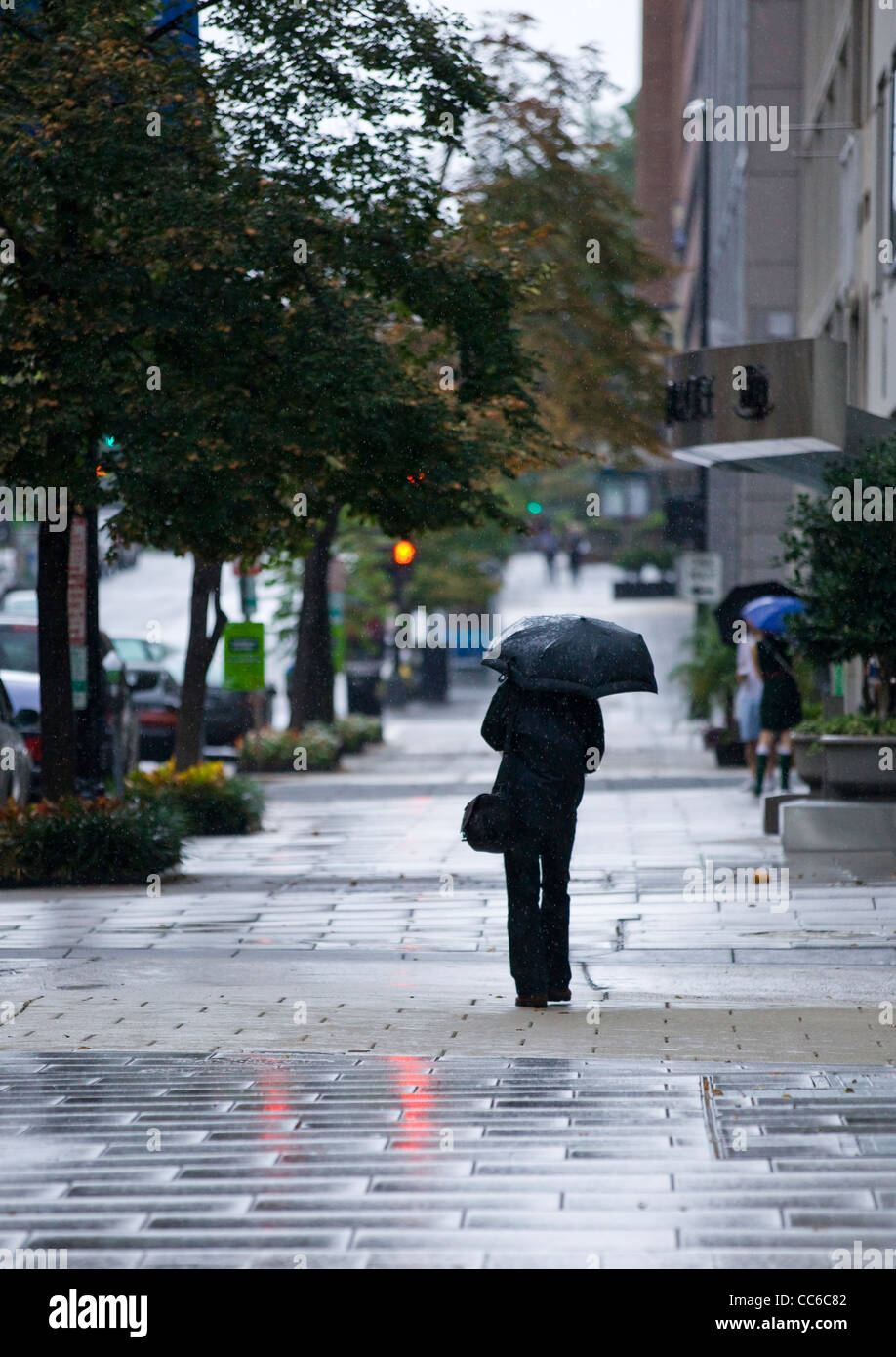 A man walking on the sidewalk with an umbrella on a rainy day Stock ...