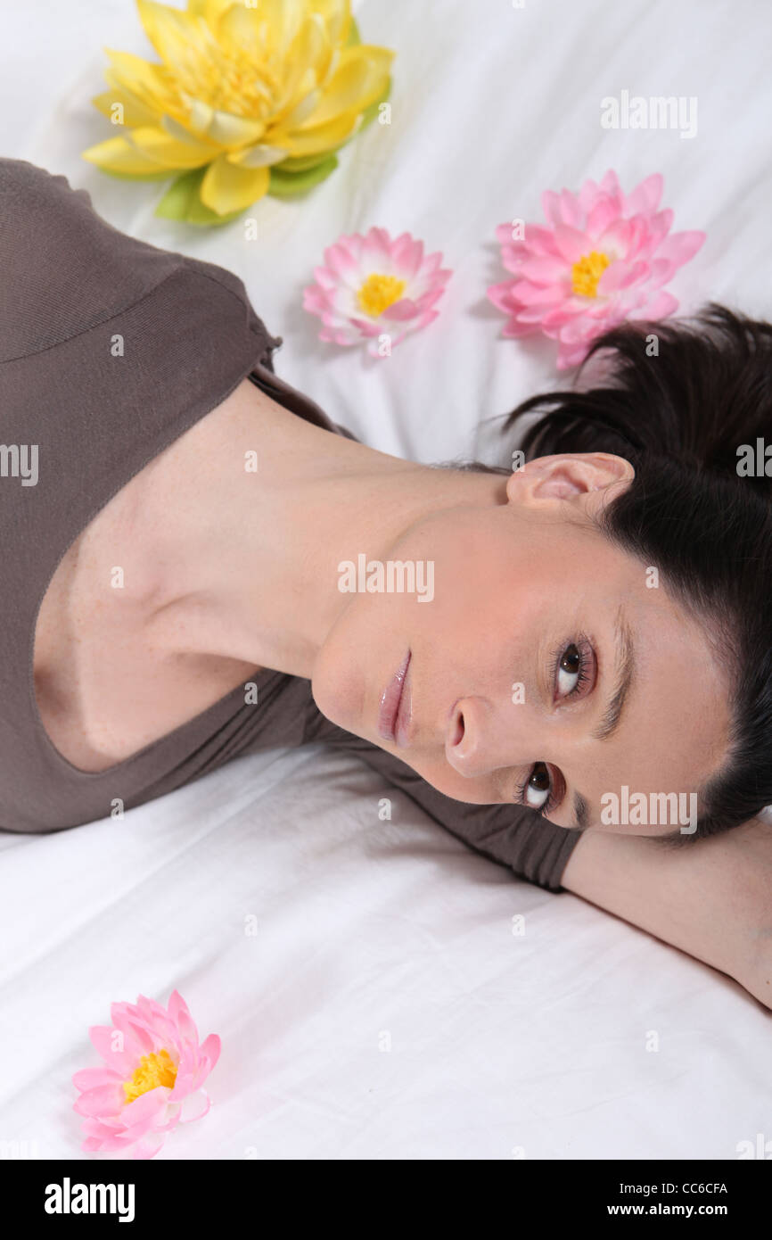 Young woman laid on a bed with flowers Stock Photo - Alamy