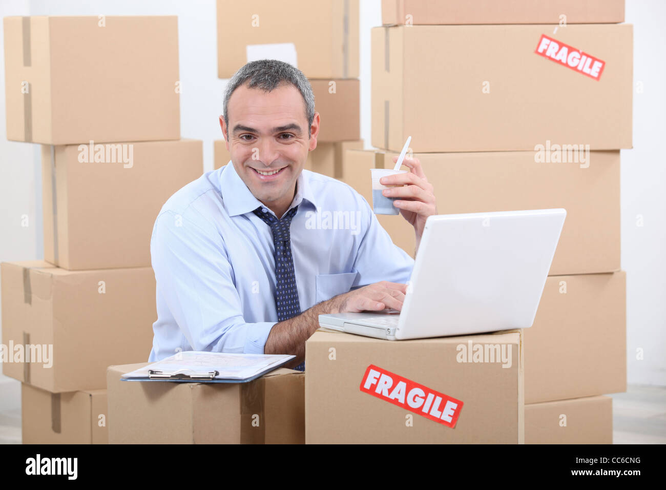 a business man drinking doing computer among cardboard boxes Stock ...