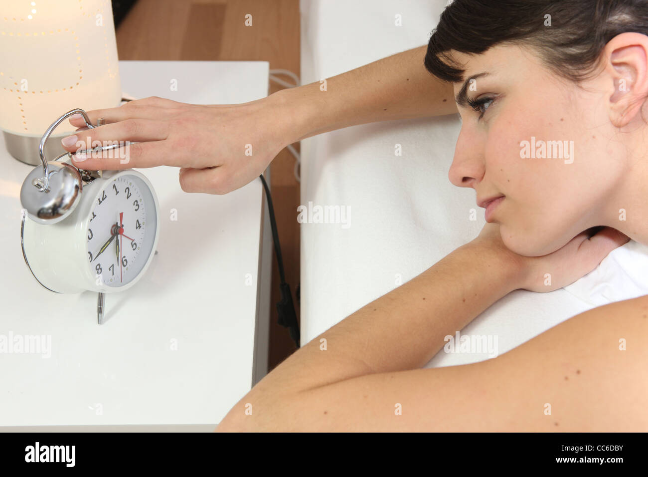 Girl turning off her clock Stock Photo - Alamy