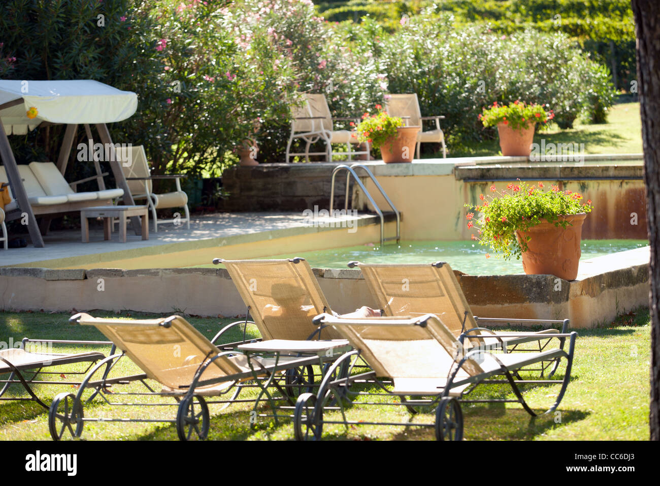 A row of chaise lounges sit poolside at a Chateau in Loriol-du-Comtat ...
