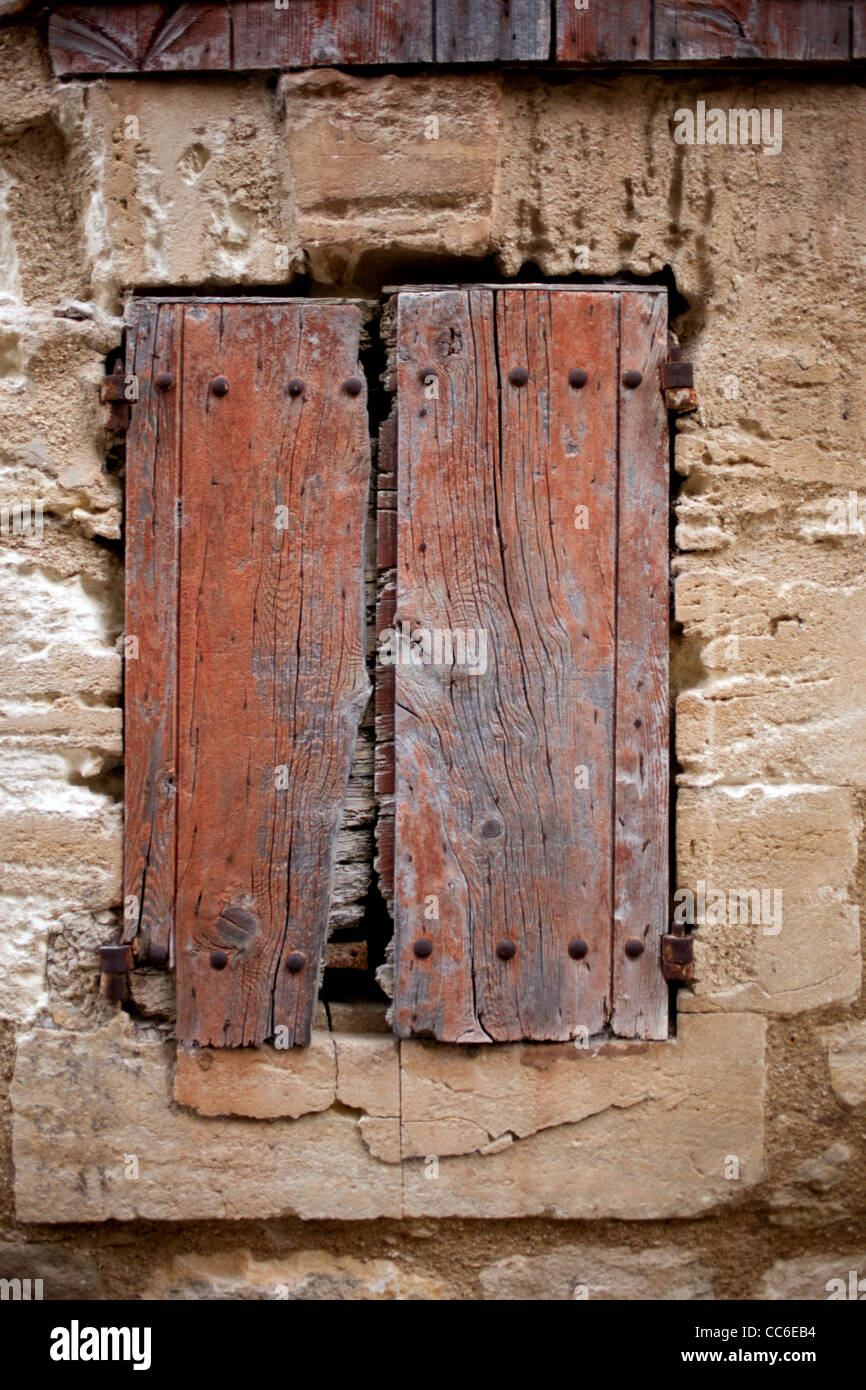 An old wooden shutter barely stays together to cover a window in ...