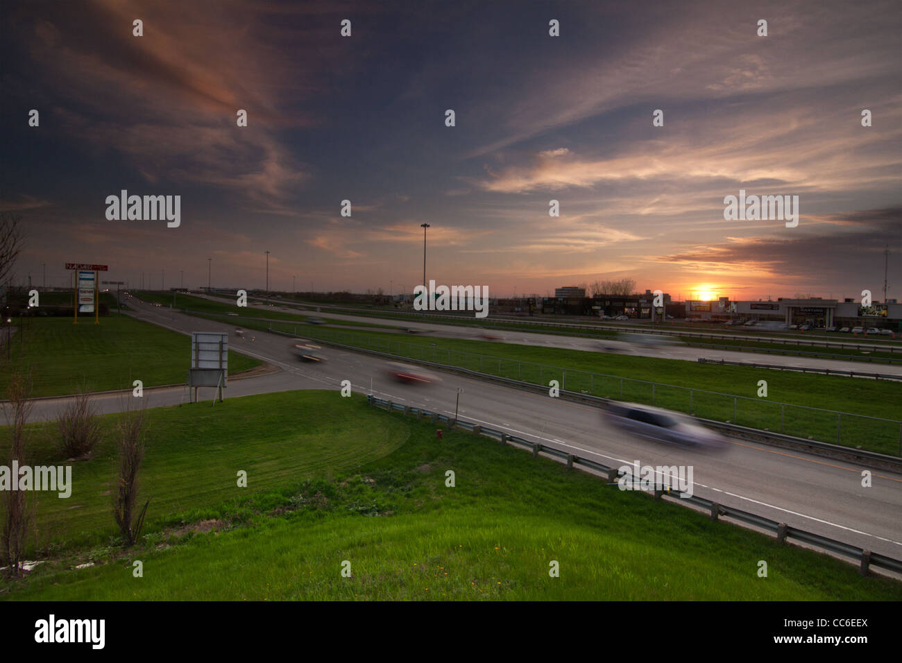 Highway in sunset, green grass and cars in full speed. the speed is ...