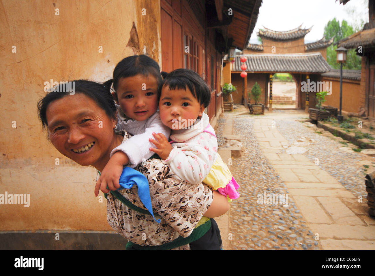 Two girls on her mother's back, Shaxi Ancient Town, Dali, Yunnan ...