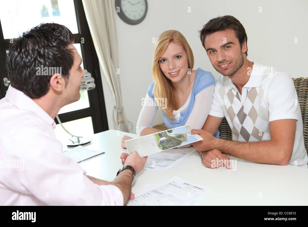 Young couple sat with estate agent Stock Photo - Alamy