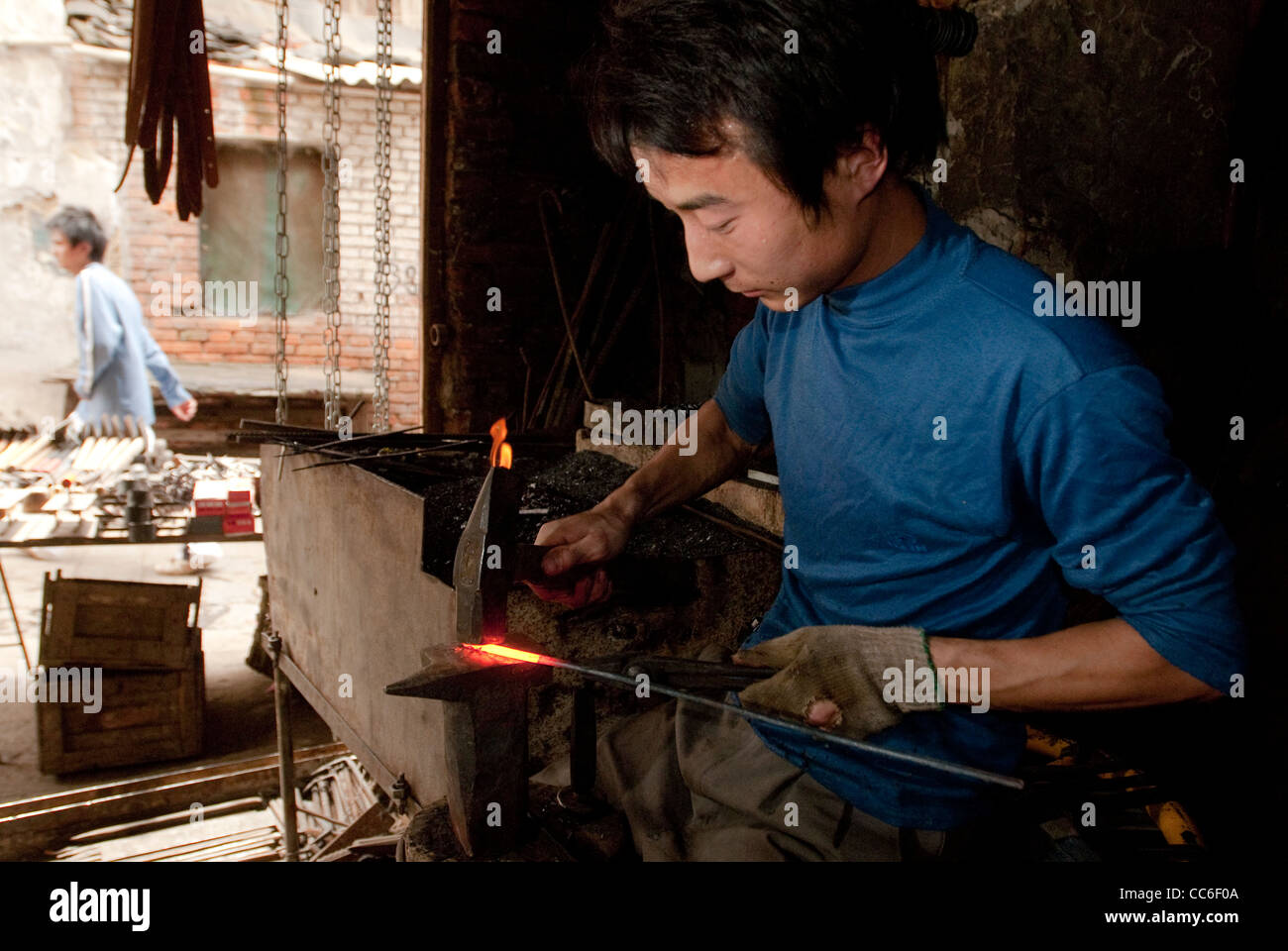 Blacksmith striking hot iron in a workshop, Zhaotong, Yunnan , China ...