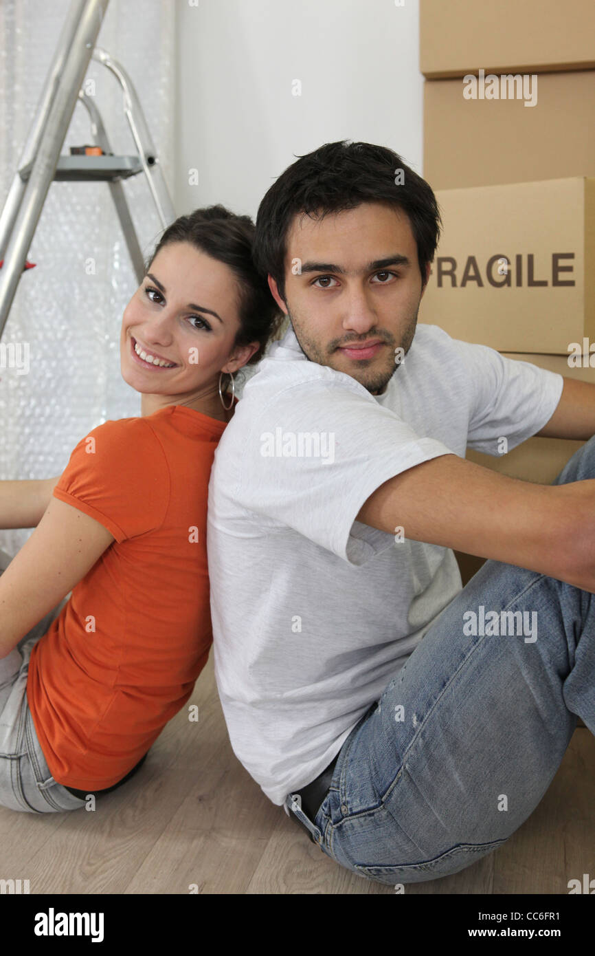 Couple sat by ladder and boxes Stock Photo - Alamy